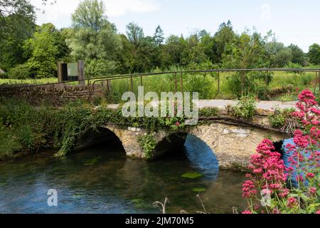 The beautiful stone footbridge covered with flowers. Bibury, England ...