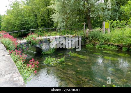 The beautiful stone footbridge covered with flowers. Bibury, England ...