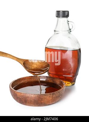 Pouring of tasty maple syrup from bottle into spoon on white background ...