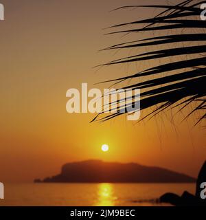 A red burning sunset over the sea with rocky volcanic cliff. Abstract ...