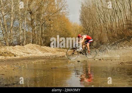 Cyclist crosses a stream with his bike and churns up the water Stock ...