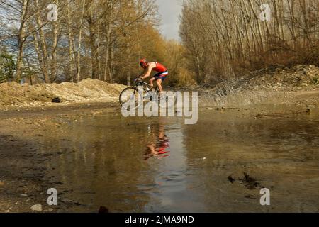Cyclist crosses a stream with his bike and churns up the water Stock ...