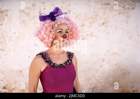 Concentrated middle aged female circus artist in funny costume and pink ...