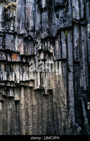 Rocky textured columns of massive basalt cliff located in Iceland as ...