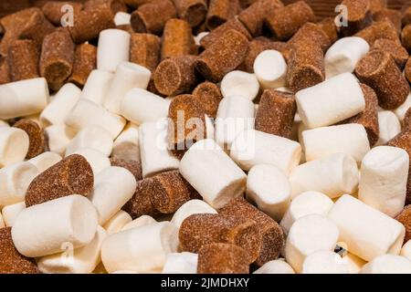 Many cylindrical chewing sweets in sugar sprinkles of white and brown ...