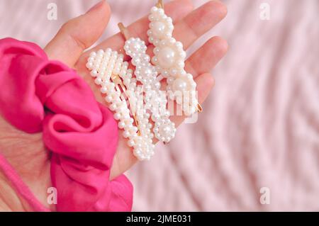 Set of pearl hairpins and elastic bands on pink background . High ...