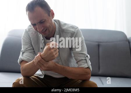 Man's arm touches a painful wrist caused by work Stock Photo - Alamy