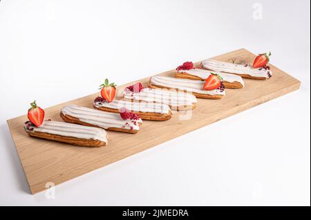 Wooden board with tasty eclairs isolated on white background Stock ...