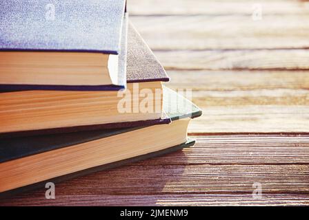 Books stacked on wooden desk in university or public library room or ...
