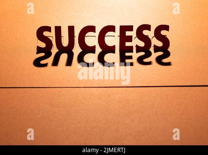 Success word cutting and standing from paper, lit from behind and ...