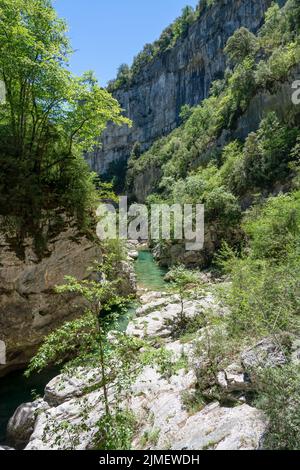 an emerald coloured river winds through a rocky gorge, summer sunshine ...