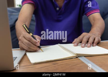 Asian elderly man holding pen write message note and computer laptop on ...