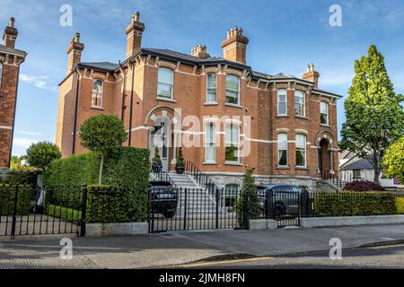 A pretty brick building in Dublin Ireland with parked cars on a sunny ...