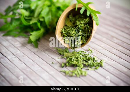dried green organic arugula, seasoning, on a light wooden background ...