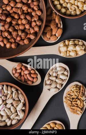 Wooden bowl and spoon with tasty macadamia nuts on blue background ...