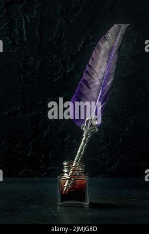 A quill pen with an old inkwell, side view on a black background with a ...