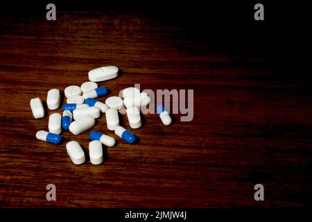 Simple pile of white and blue pills, medicines, pills stacked on brown ...