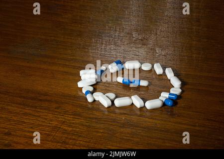 Simple pile of white and blue pills, medicines, pills stacked on brown ...