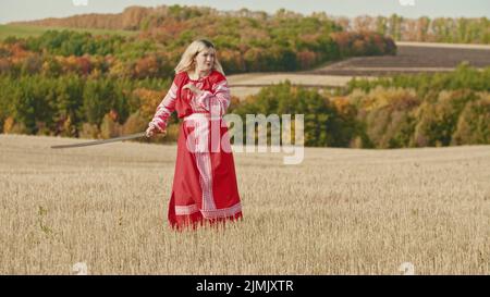 Training in the autumn field - a belligerent woman wields with a sword ...