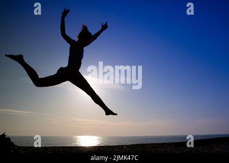 Dance jump performed outdoors in backlight Stock Photo - Alamy