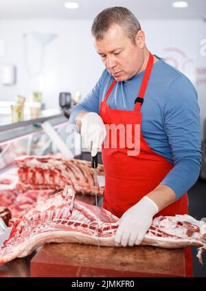 Serious seller splitting of pig carcass in shop Stock Photo - Alamy