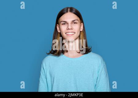 Headshot portrait of smiling teenage guy on blue studio background ...