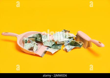 Creative layout with dustpan, hand brooms and crumpled money dollar ...