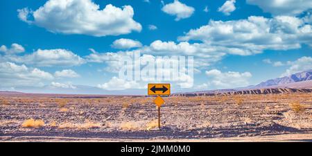 Directional sign in the desert with scenic blue sky and wide horizon ...