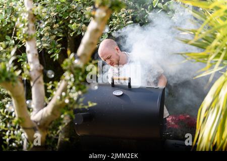 A bald Caucasian man grilling barbeque outdoors Stock Photo - Alamy