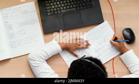 Cute boy with laptop doing homework in classroom at school Stock Photo ...