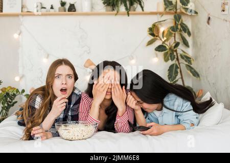 Girls lying bed eating popcorn having fun Stock Photo - Alamy