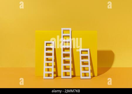 Ladders arrangement with yellow background Stock Photo - Alamy