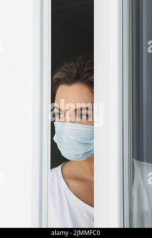 Scared woman is looking through the window. Having bruise on her face ...