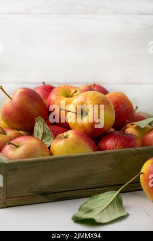 Fresh farmer apples in wooden crate harvest fruits on light surface ...