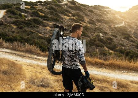 Professional downhill rider carrying his bicycle on shoulder Stock ...