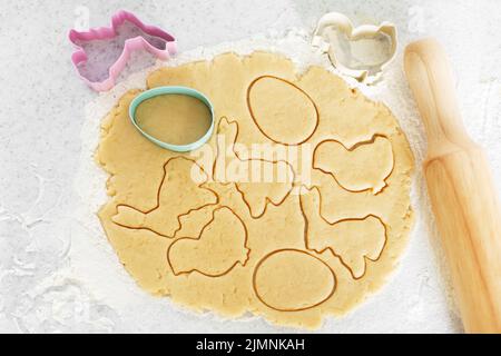 Dough with cookie cutters and rolling pin on kitchen table Stock Photo ...