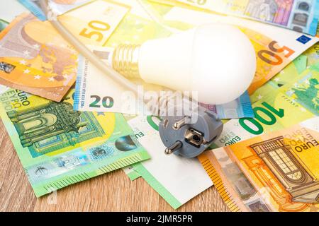 Electric plug and lightbulb on euro banknotes Stock Photo - Alamy