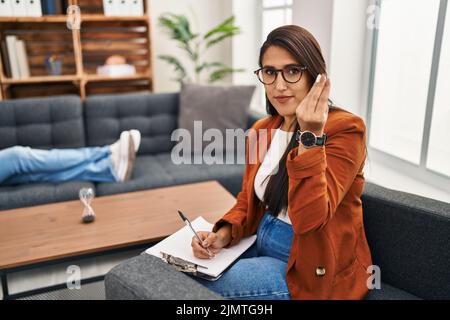 Young hispanic woman working at psychology clinic doing stop gesture ...