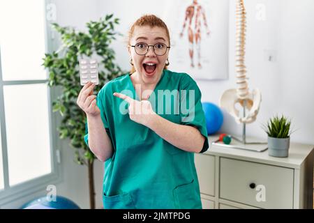 Young redhead physiotherapist woman holding question mark at the clinic ...