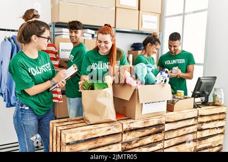 Group of young volunteers smiing happy with hands raised up at charity ...