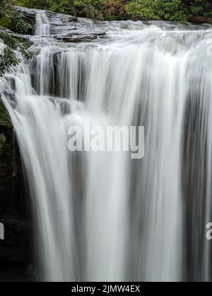 A roadside waterfall going over a cliff and over a road that is now ...