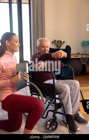 Biracial male physiotherapist looking at senior male patient at clinic ...