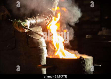 Blacksmith putting a burning item in the bucket of water - steam coming ...