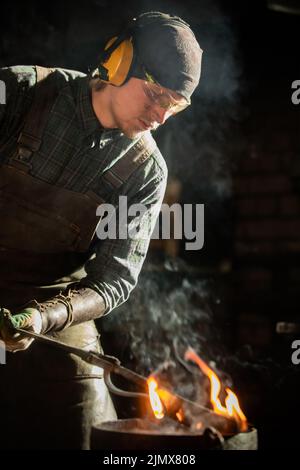 Blacksmith putting a burning item in the bucket of water Stock Photo ...