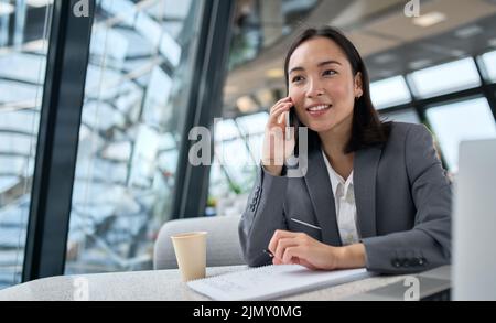 Asian young woman professional speaking on smartphone while using ...
