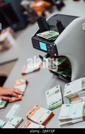 Bank employees using money counting machine while sorting and counting ...