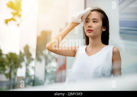 Asian beautiful business woman drying sweat her face with cloth in warm ...
