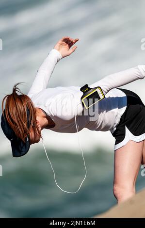 Stock image of a woman stretching before her morning beach run. Runner ...