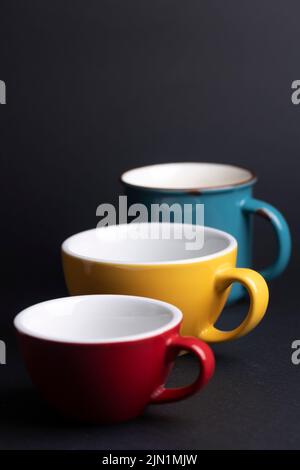 bright ceramics - cups in yellow, blue, red and pink colors on a black ...