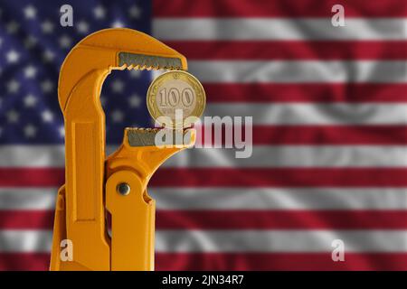 100 Kazakhstani tenge held in an orange plumber wrench on a pink ...